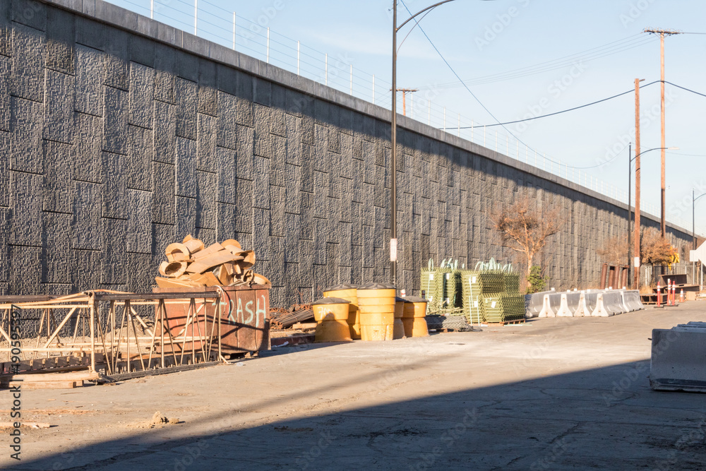 Staging area of road construction materials behide a concrete retaining ...