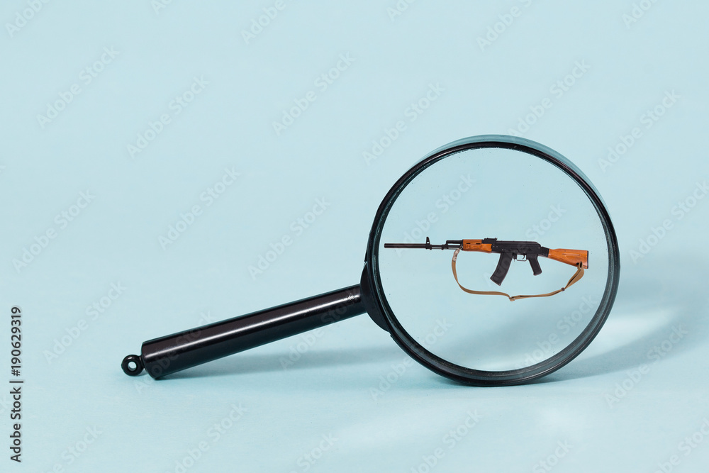 A shotgun under the magnifying glass on a light blue background. Stock ...