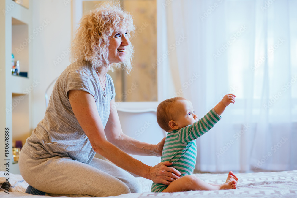 Beautiful curly blond grandmother with her infant baby grandson sitting ...