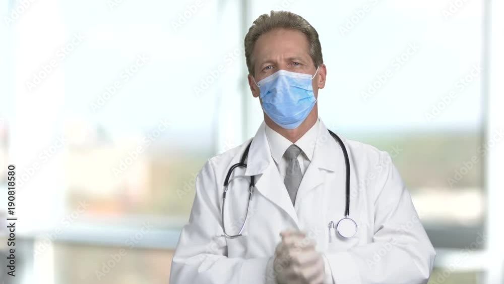 Friendly doctor putting on sterile gloves. Handsome male surgeon fold ...