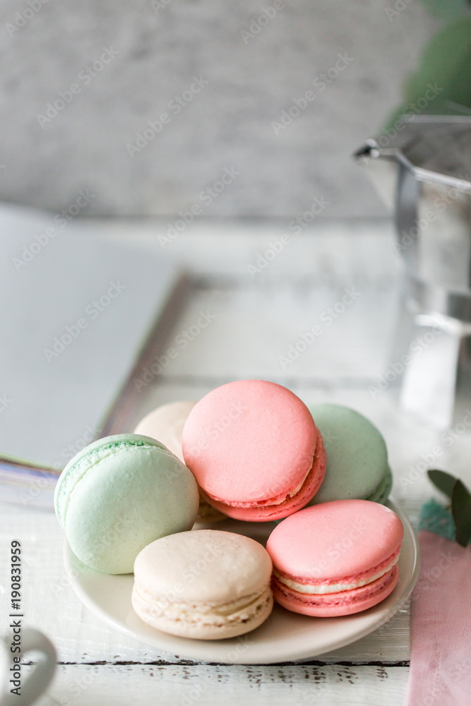 Colorful French or Italian macarons stack on white plate put on wood ...