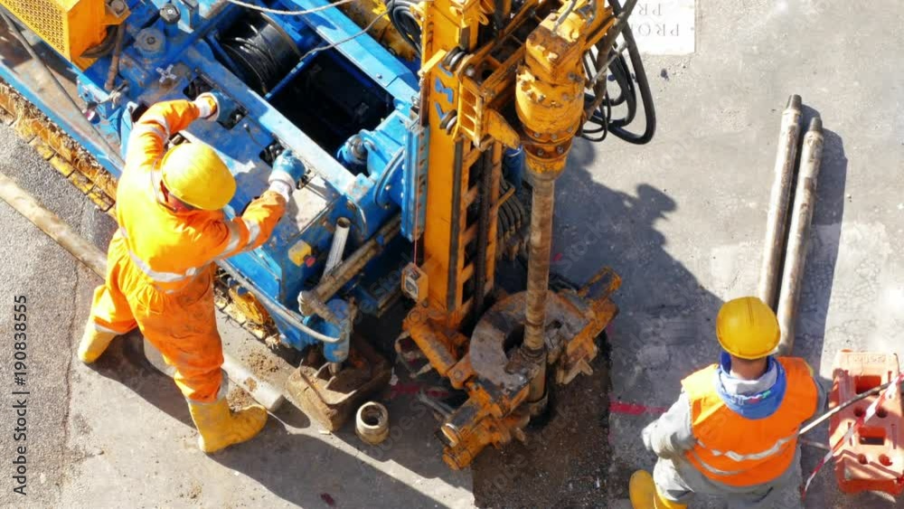 Two men operating powerful metal drilling rig in the centre of the ...