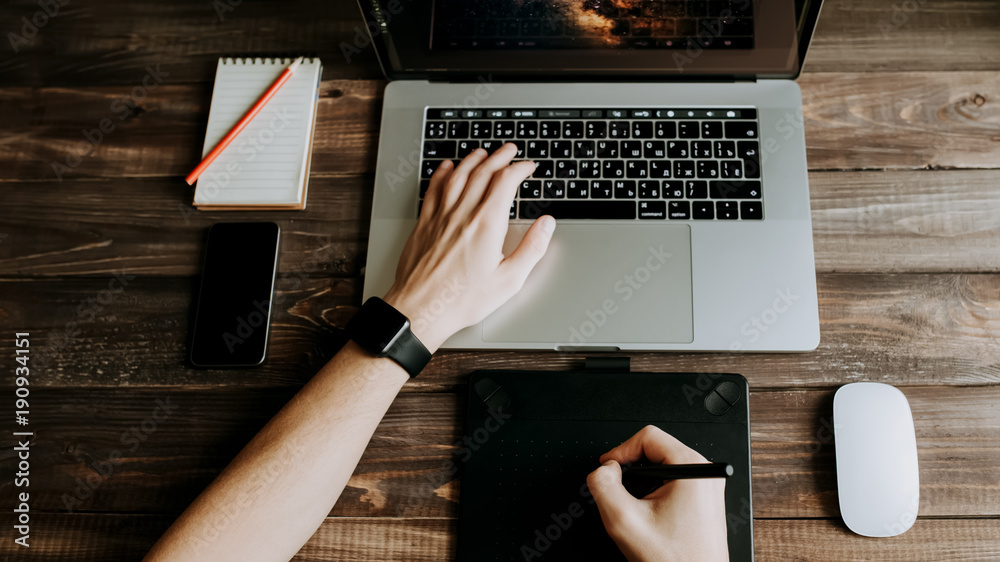 Man designer is working using laptop computer and graphics tablet at ...