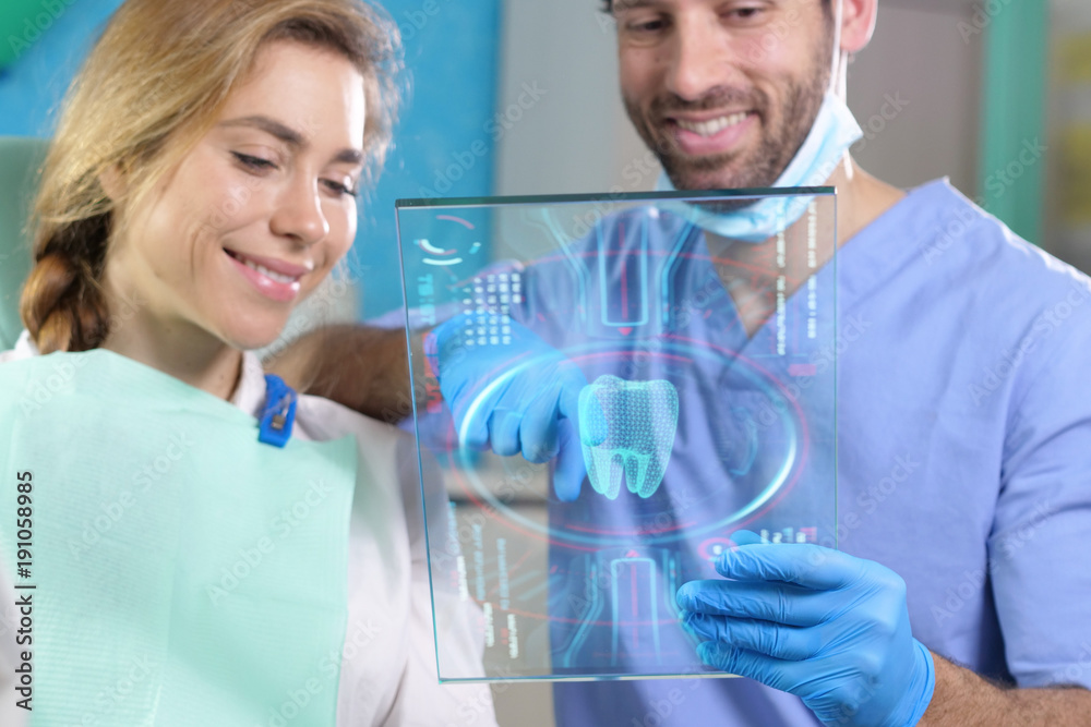 A futuristic dentist shows the futuristic holographic plate of the patient's dentition, and she ...
