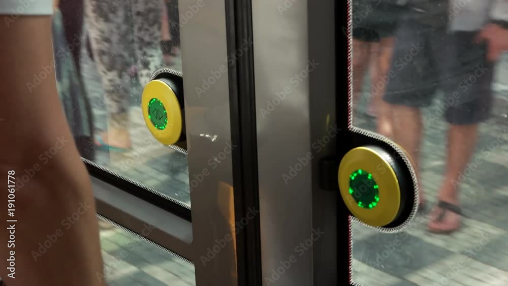 Passenger push the button on a tram doors and getting in through opened ...
