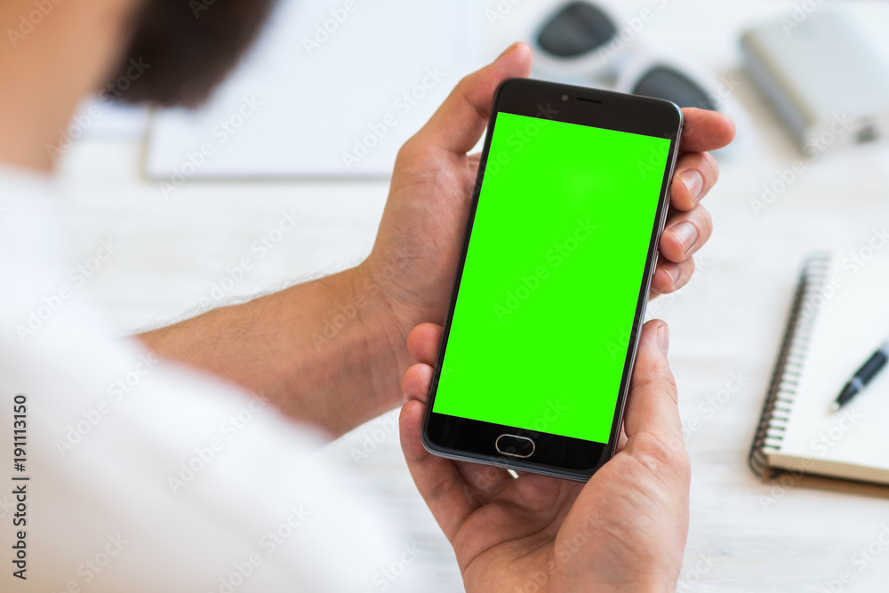 The man uses a smartphone with green screen for chroma key compositing ...