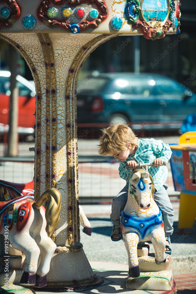 Vintage carousel in amusement park. Boy is riding a toy horse in summer ...