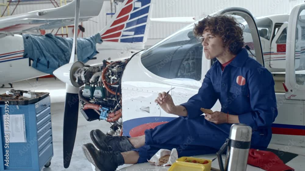 Female aircraft mechanic sitting on wing of light jet airplane in ...