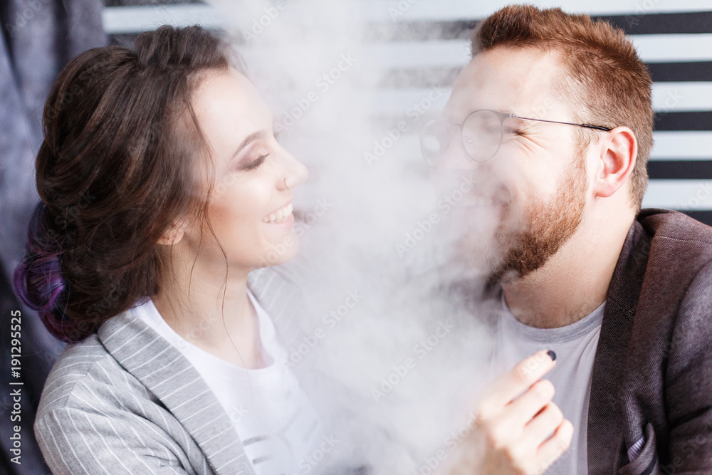 Couple vaping. Young man and woman blowing smoke at black and white ...