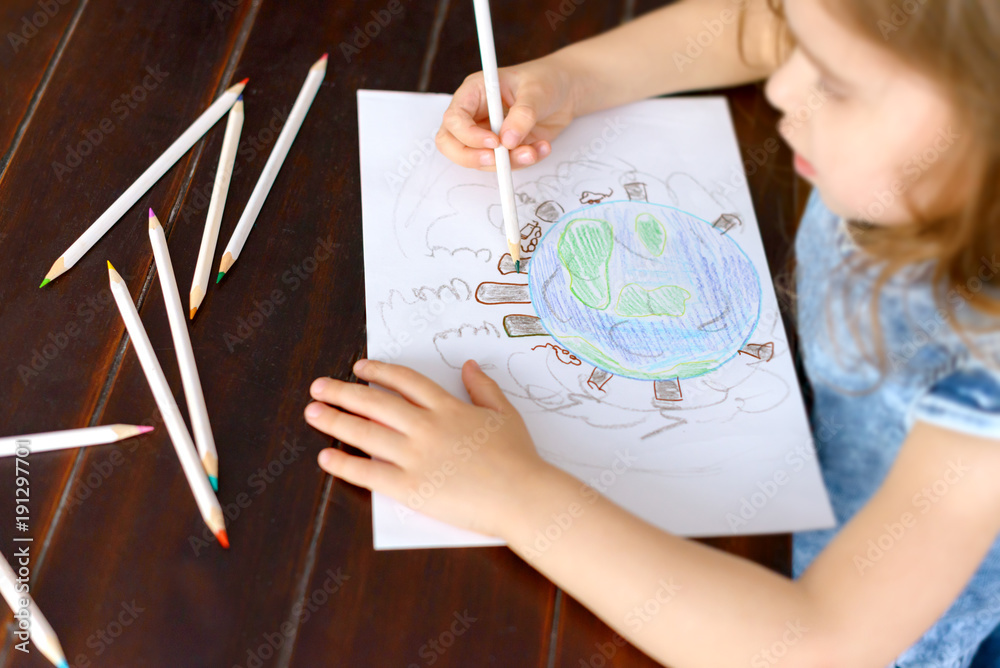 Portrait of cute little girl creating art on paper with colored pencils ...