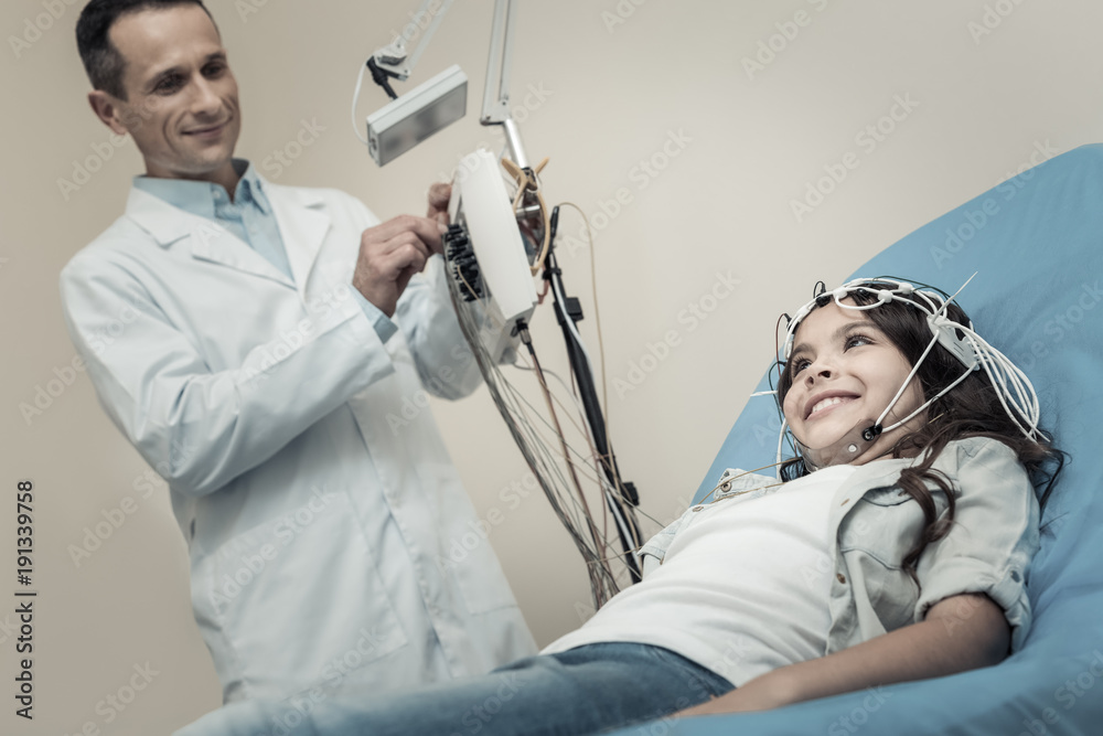 Ready for examination. Cheerful positive excited girl lying on the bed ...