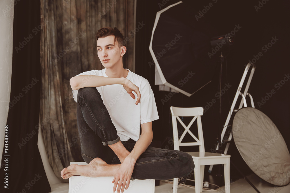 A handsome male model, in a photo studio. On the background of studio ...