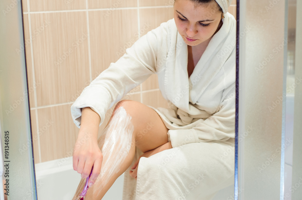 beautiful girl shaving her legs using a razor while taking shower in ...