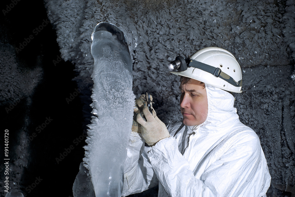 cave explorer examines the ice stalagmite on the background of a dark ...
