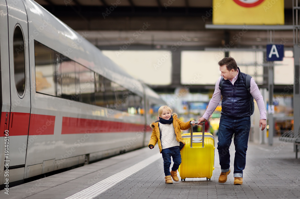 Cute little boy and his father waiting express train on railway station ...