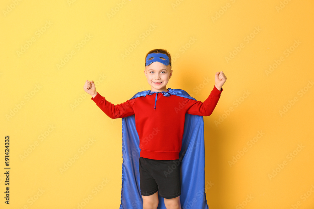 Cute boy in superhero costume on color background Stock Photo | Adobe Stock