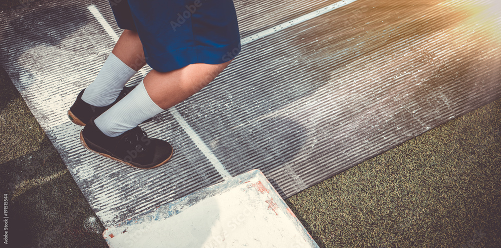 Students boy taking long jump on rubber board during a school sport ...