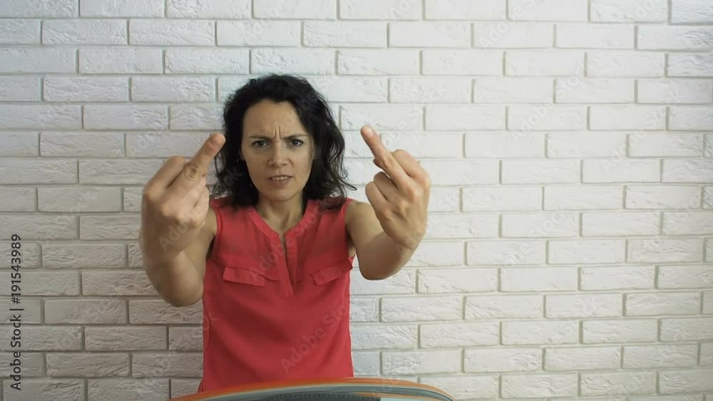Middle Finger. An angry woman with a suitcase shows her middle finger ...