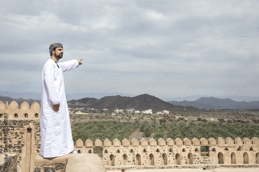 arab man in traditional omani outfit pointing to the distance in Omani ...