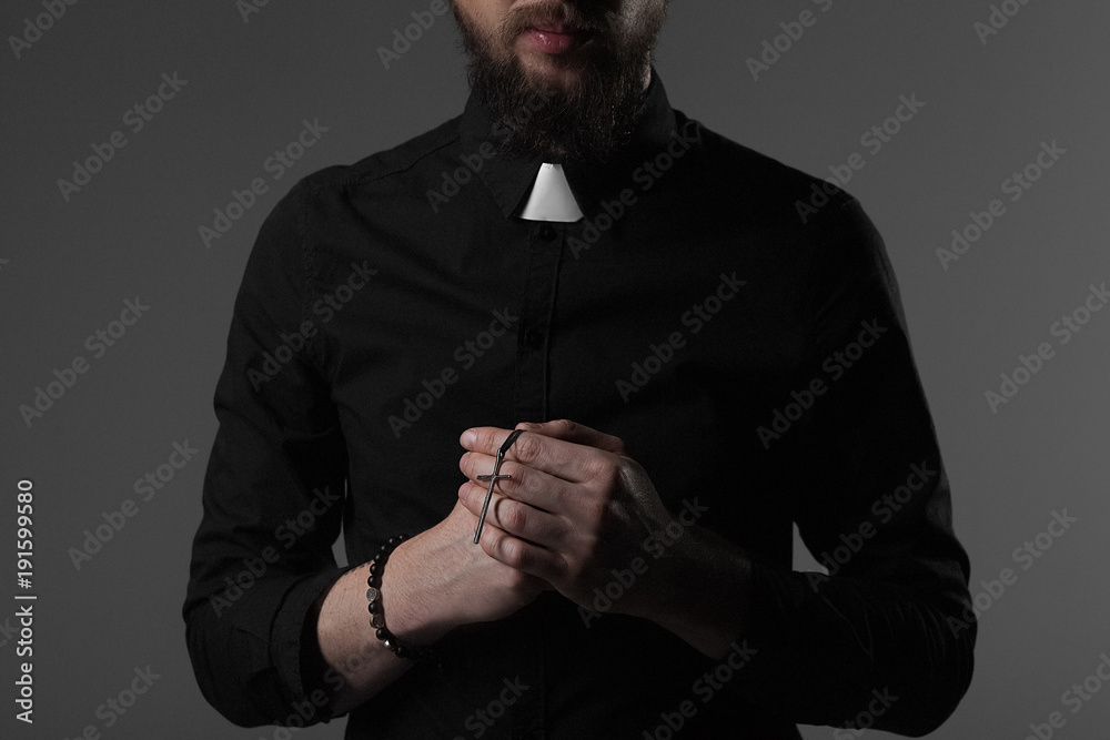 the priest stands straight without a face with his hands and a cross on ...