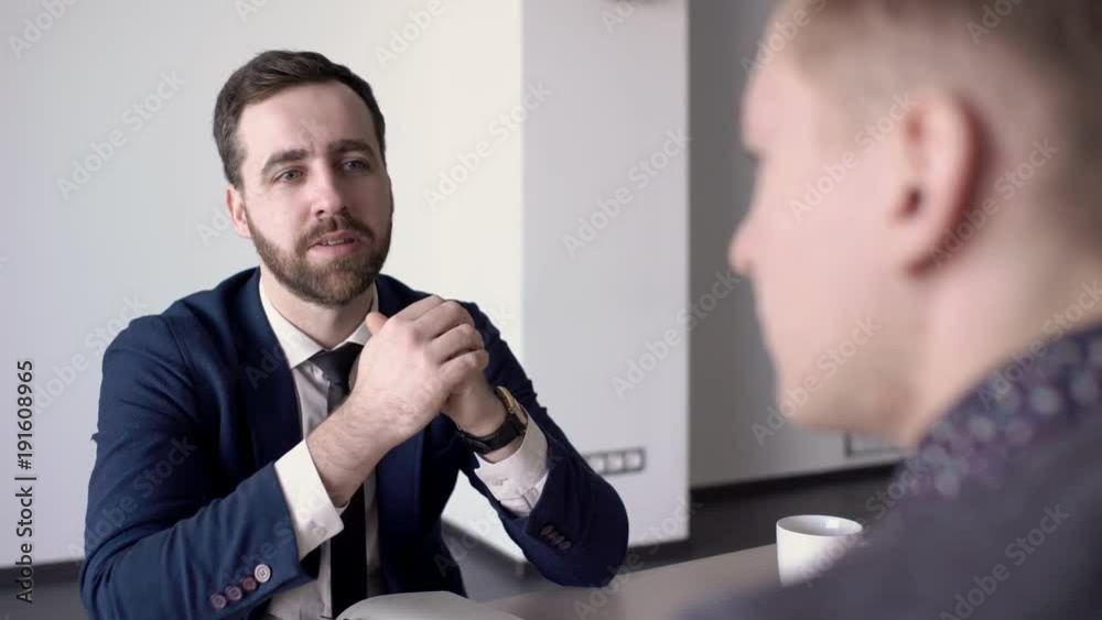 Young boss is communicating with male employee in modern office. Two ...