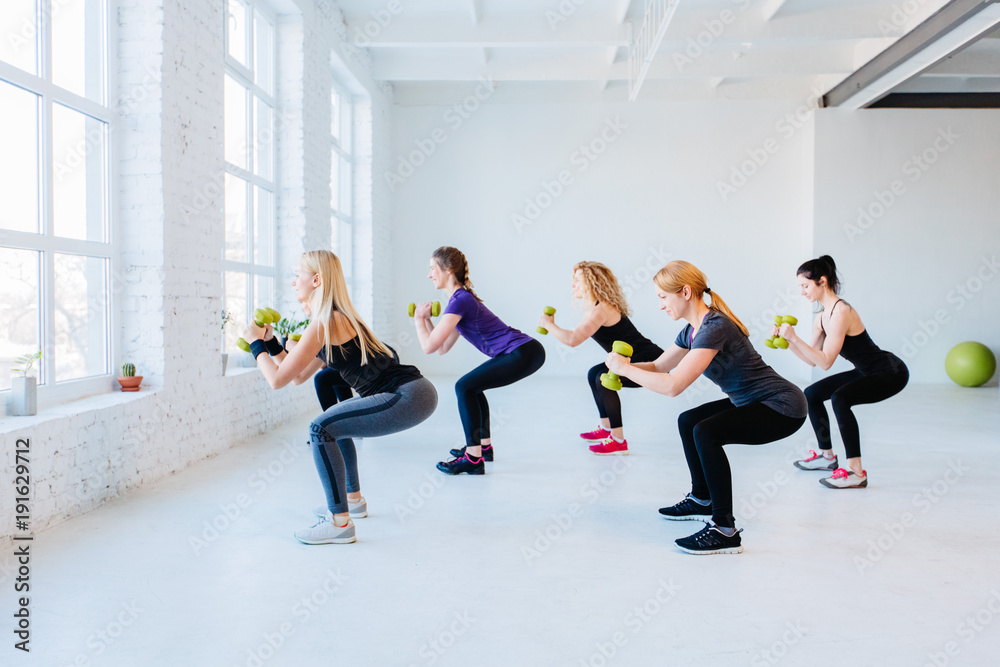 Side view group of six athletic women doing squatting exercises with ...