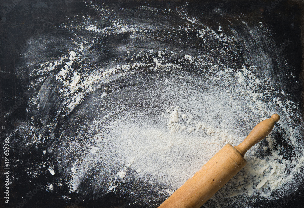 Baking background with the rolling pin and flour. On the dark table ...