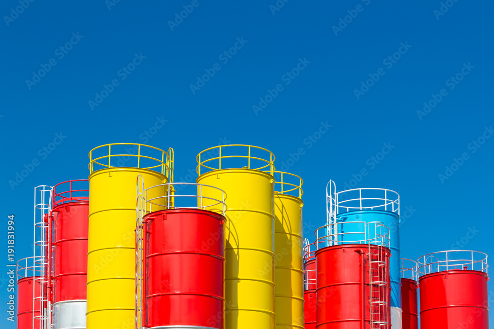 many color steel storage tanks against blue sky, metal silos for ...