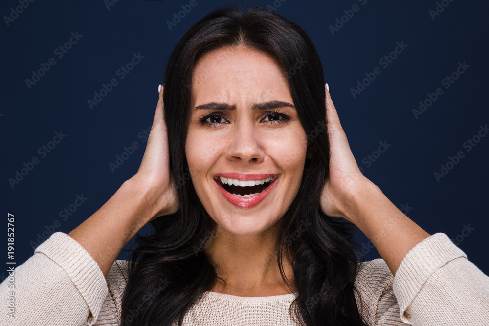 So loud. Portrait of beautiful young woman making face and covering her ...