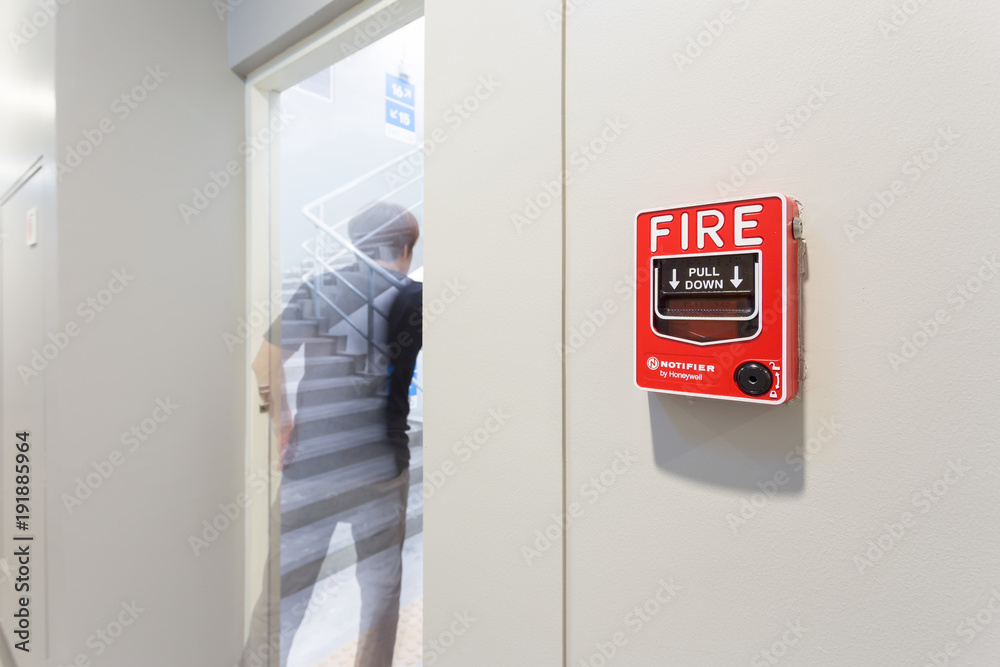 The man running open emergency exit door is and fire alarm on the wall ...
