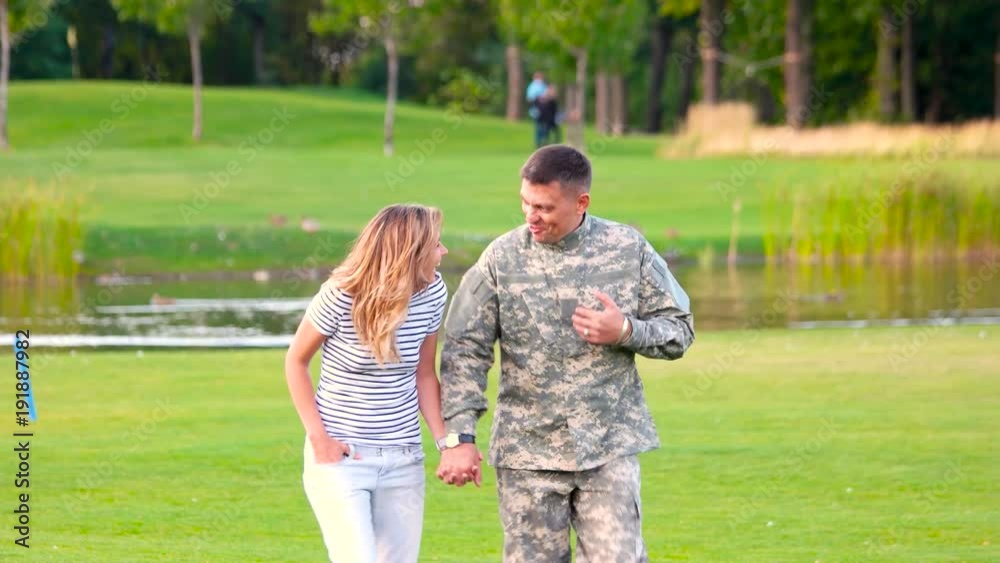 Lovely couple walking together in the park. Military army soldier with ...