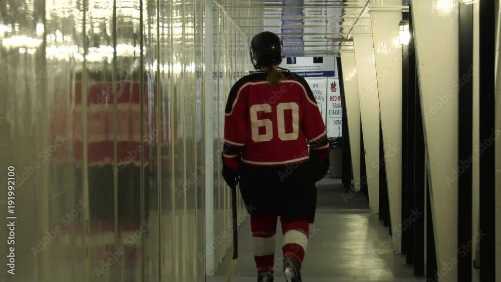 female hockey player walks down hallway to get to ice depth of field ...