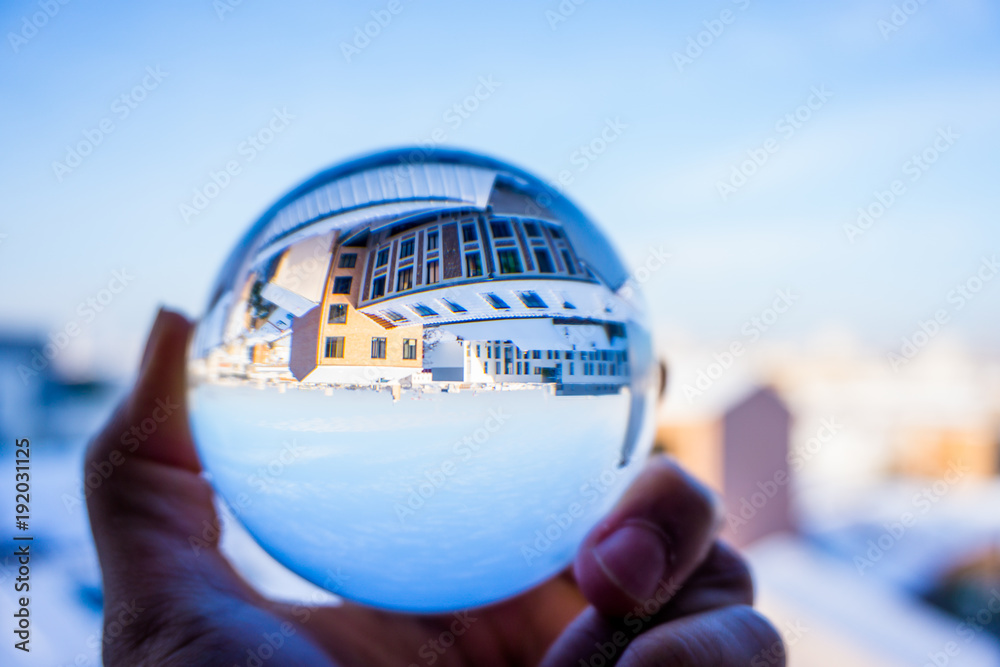 A hand holding a crystal ball for optical illusion. City as the ...