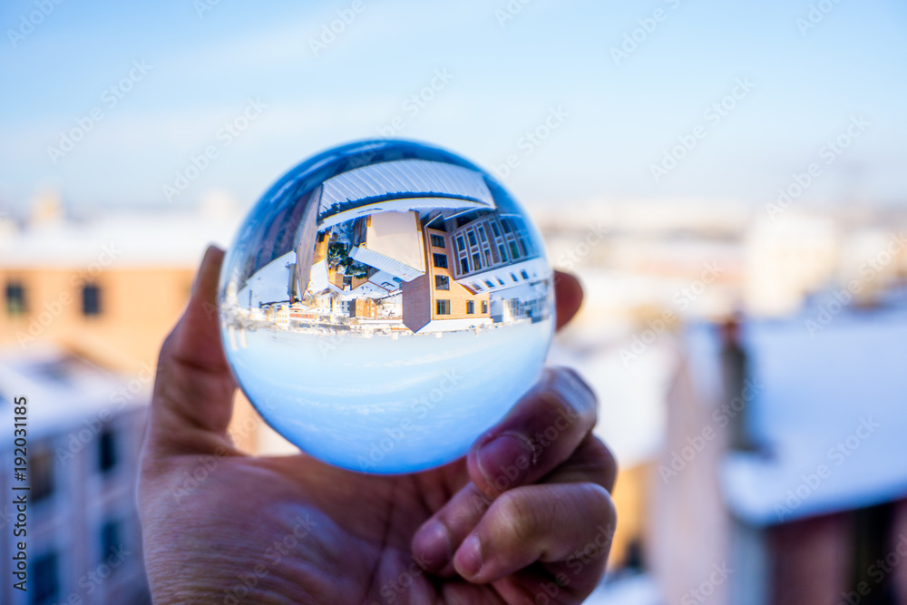 A hand holding a crystal ball for optical illusion. City as the ...