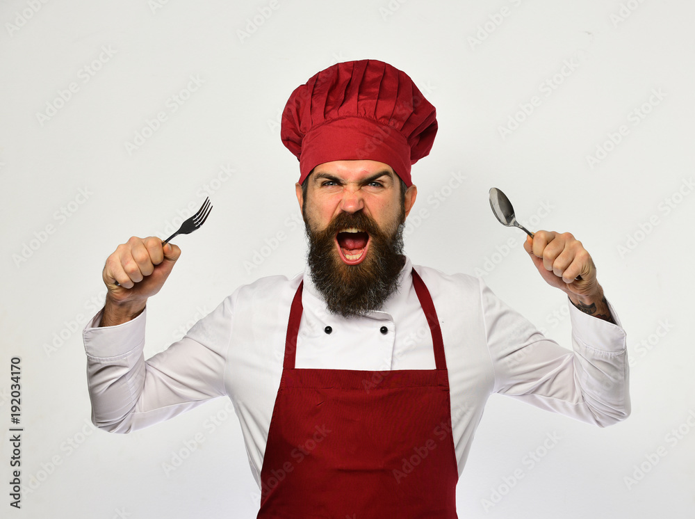 Cook with angry face in burgundy uniform shows cutlery Stock Photo ...