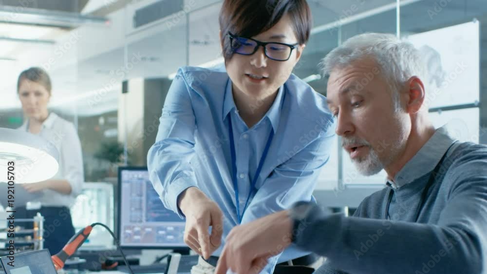 Two Engineers Talking while Working with Robot, Manipulating its ...