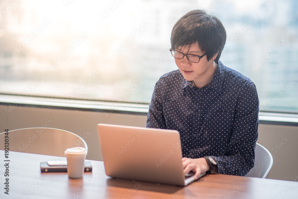 Young Asian businessman working with his laptop computer in office ...