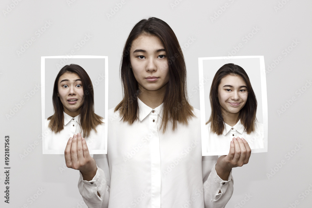 Indoor photo of woman holding two different portraits of herself with ...