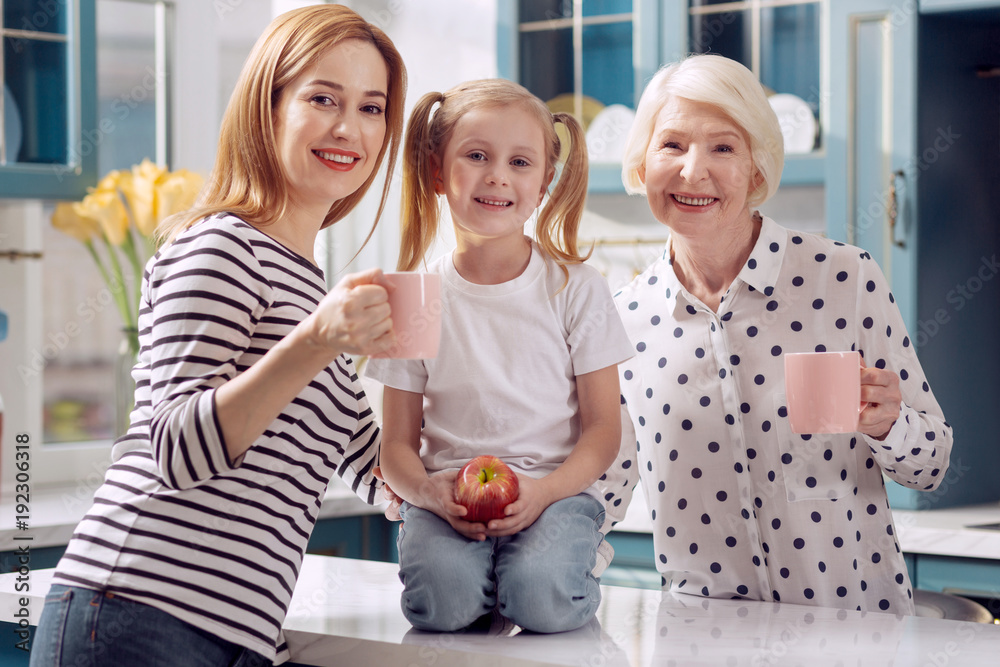 Happy relatives. Adorable little girl sitting on the kitchen counter ...
