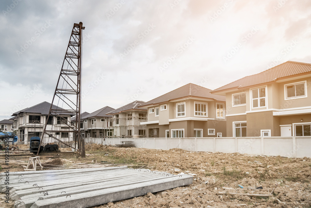 house building at construction site with pile driver and concrete piles ...