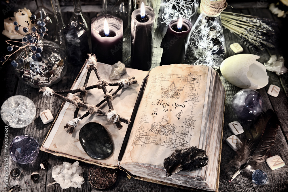 Open witch book with pentagram, black candles, stones, crystals and ...