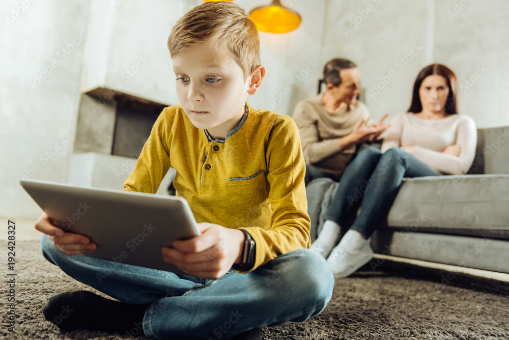 Being lonely. Sad little boy sitting cross-legged on the floor and ...