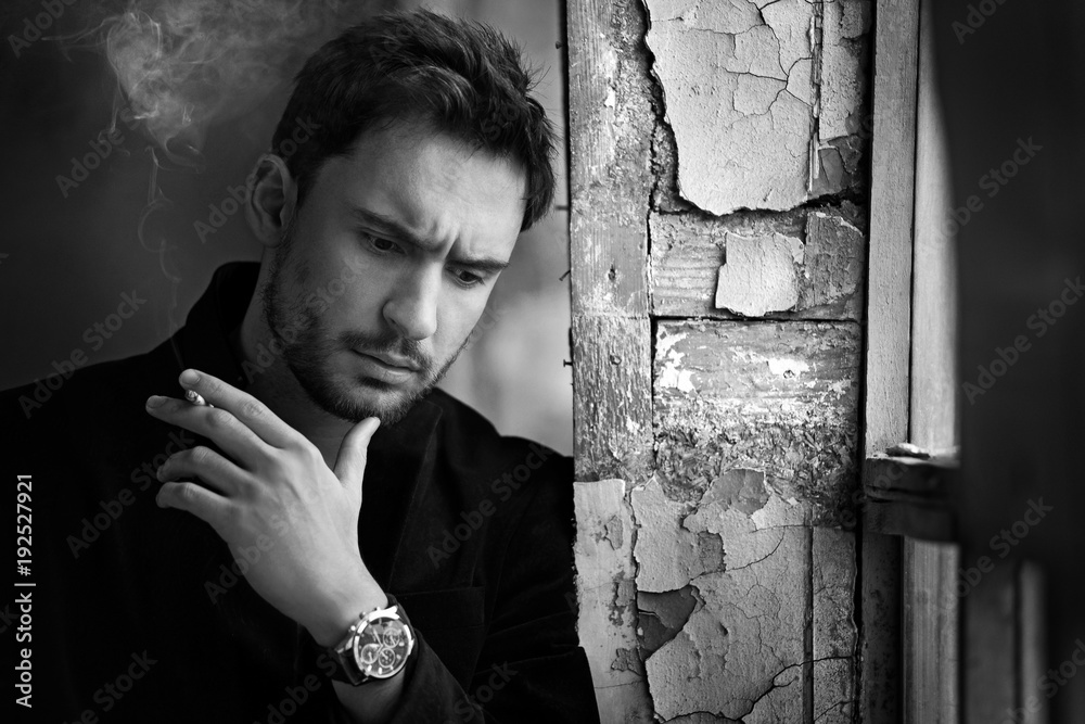 Mysterious handsome man with sneaky look. man with beard smiling. sexy guy in a dark jacket with ...