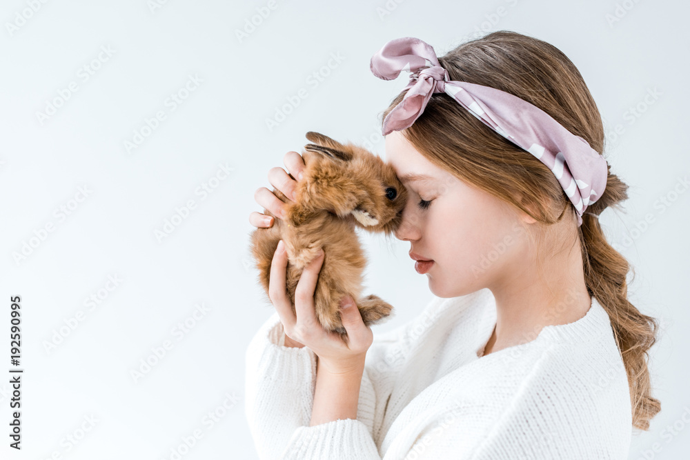 side view of beautiful little girl holding furry rabbit isolated on ...