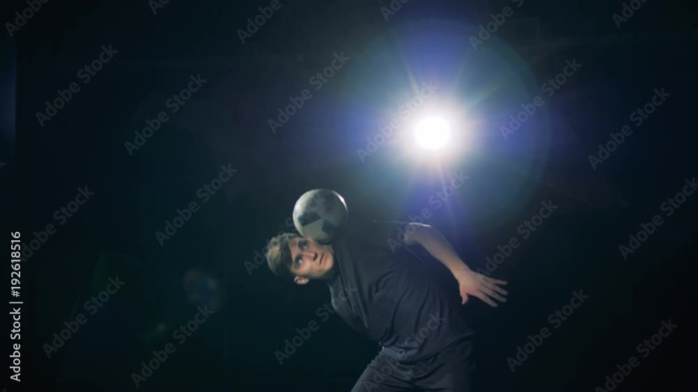 Professional soccer player is making tricks with a ball on his head ...
