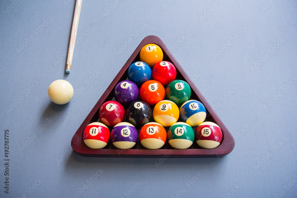 Billiard balls in a wooden rack,a cue stick and white pool ball on a ...
