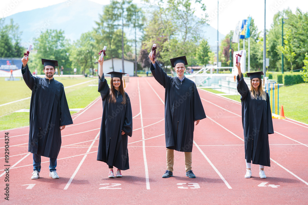 Graduation group of students celebrating on athletic track with ...