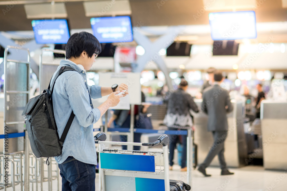 young asian man waiting for check in and dropping his luggage at ...