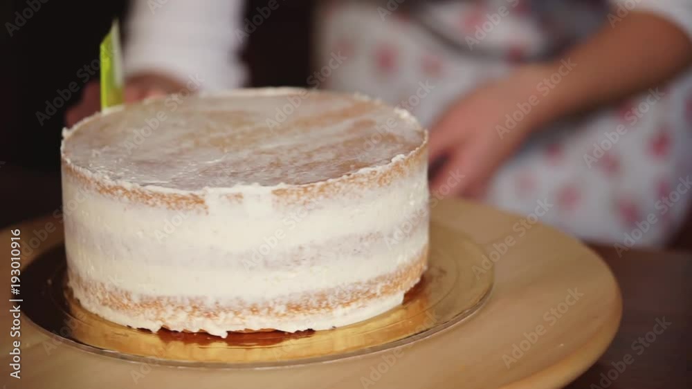 Pastry chef is rotating a plate with cream pie. She is leveling and ...