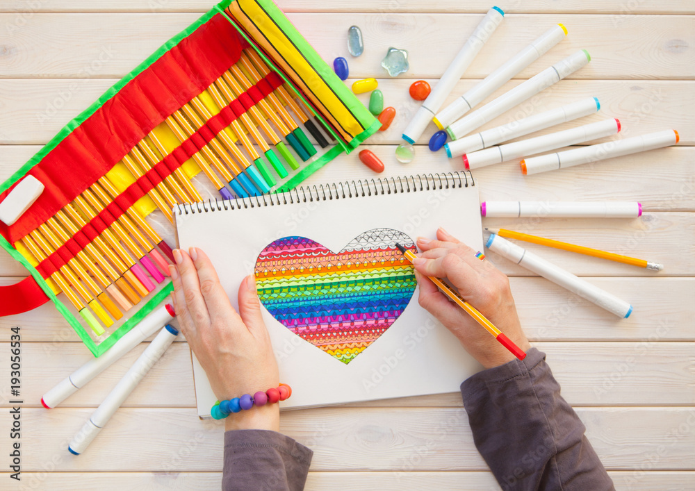 Girl draws markers postcard with a color heart. Many bright markers ...
